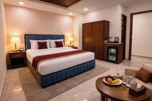 Quarto de hotel com cama grande, luminárias de cabeceira, guarda-roupa, minibar e uma pequena mesa com frutas e um copo.