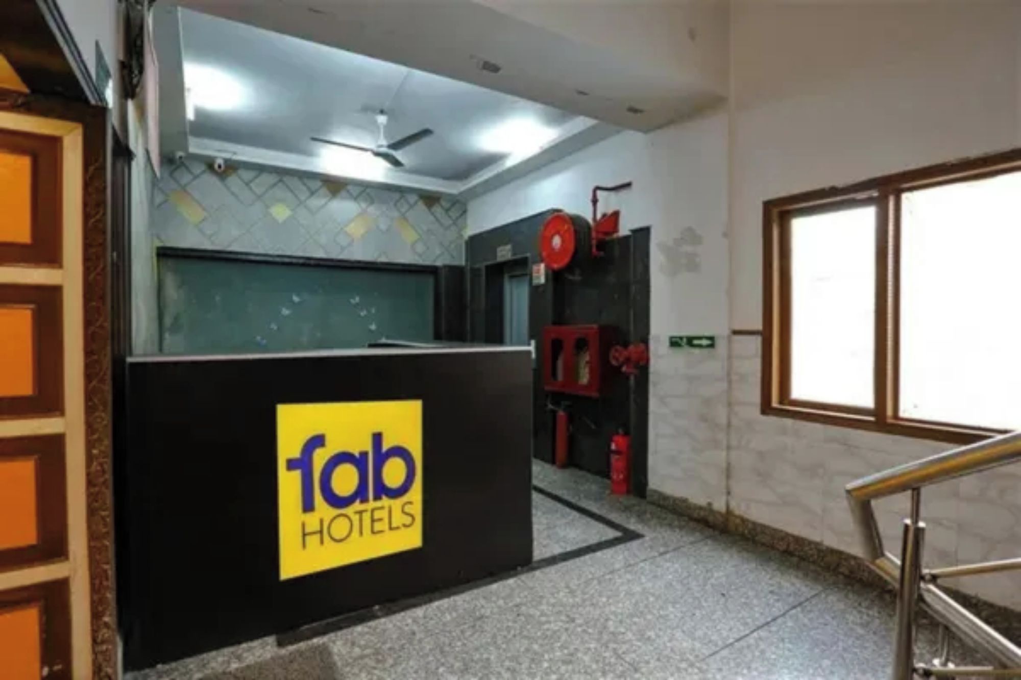 Uma receção com o logotipo 'fab hotels' e um extintor fixado na parede.