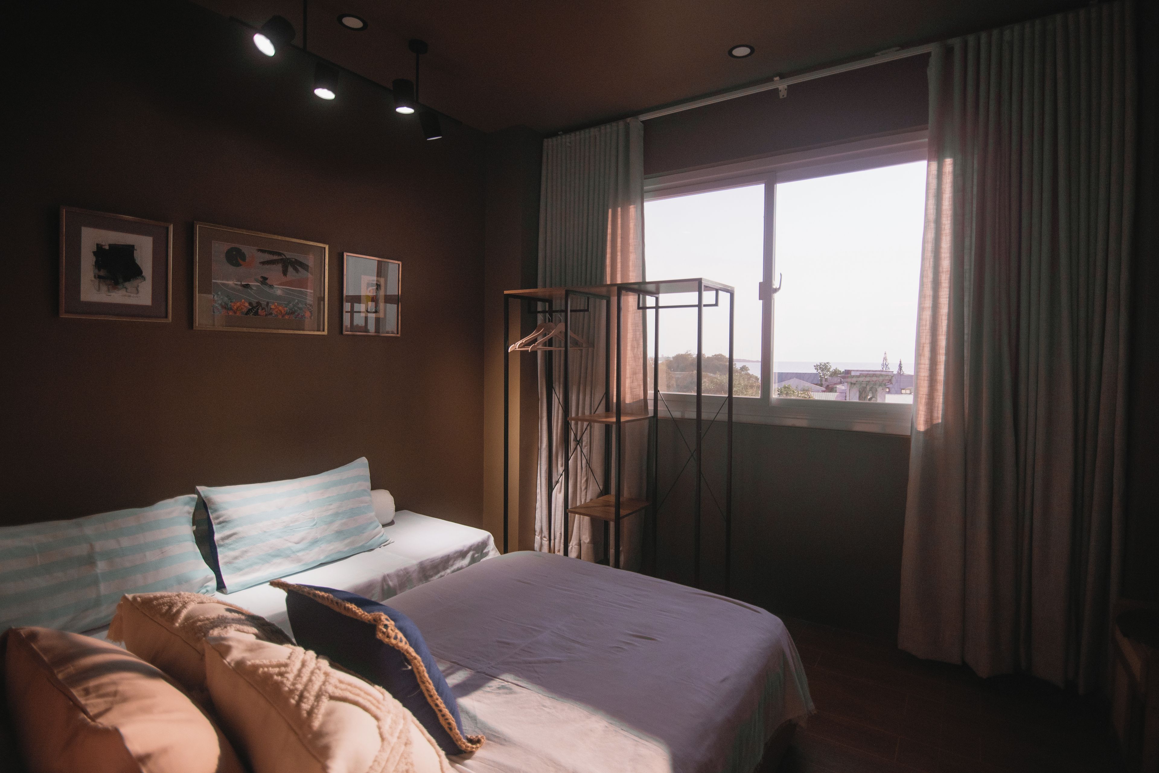 Quarto com duas camas, uma janela com cortinas e obras de arte nas paredes.