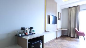 Quarto de hotel com cozinha compacta, televisão de tela plana, área de estar e piso com padrão herringbone.