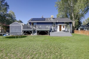 Uma casa de dois andares com deck coberto, painéis solares e quintal cercado.