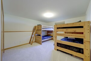Quarto com duas beliches, uma escada e teto branco.
