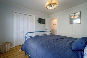 Quarto com cama, televisão na parede e porta.
