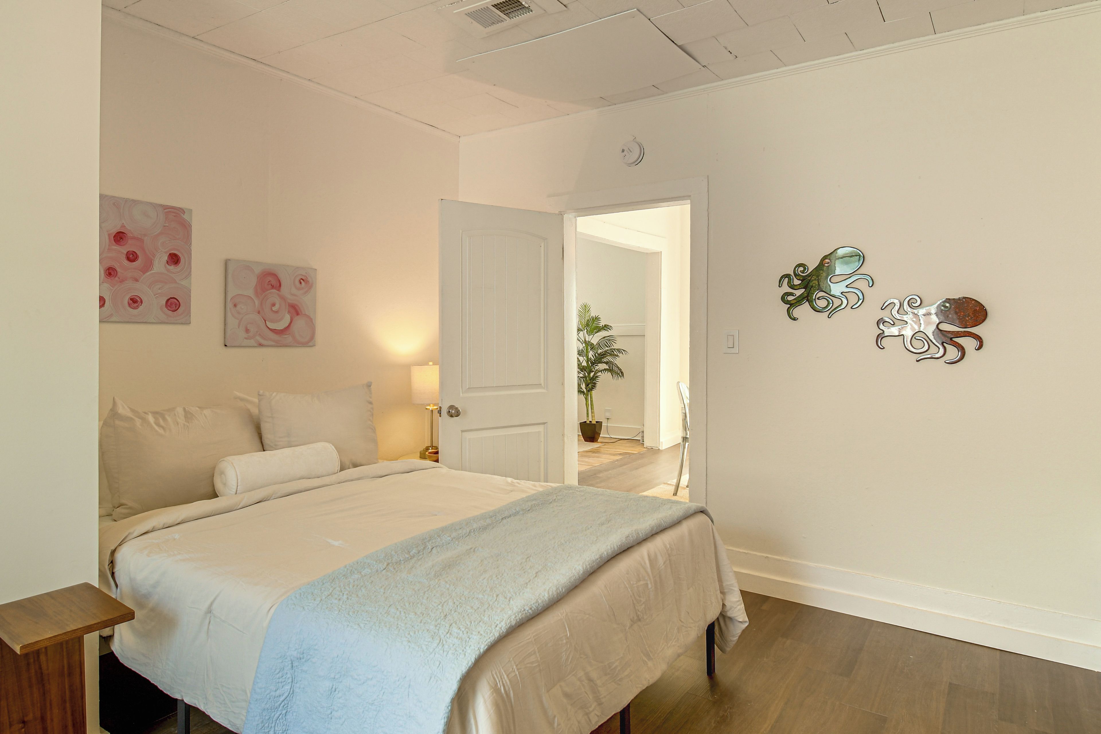 Quarto com cama, mesa de cabeceira, porta e decorações nas paredes.