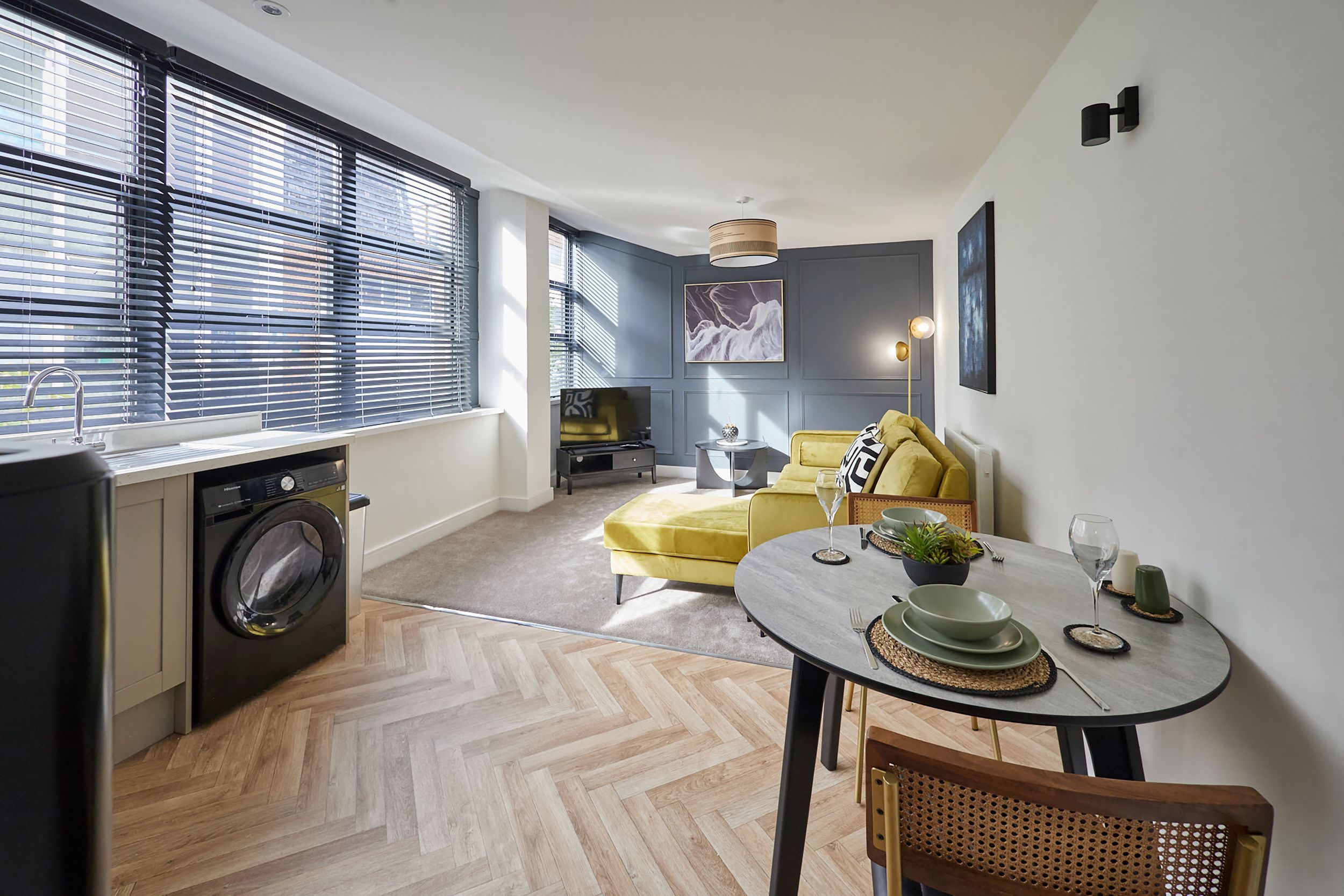 Espaço compacto com cozinha, área de refeições e sala de estar com sofá e mesa.