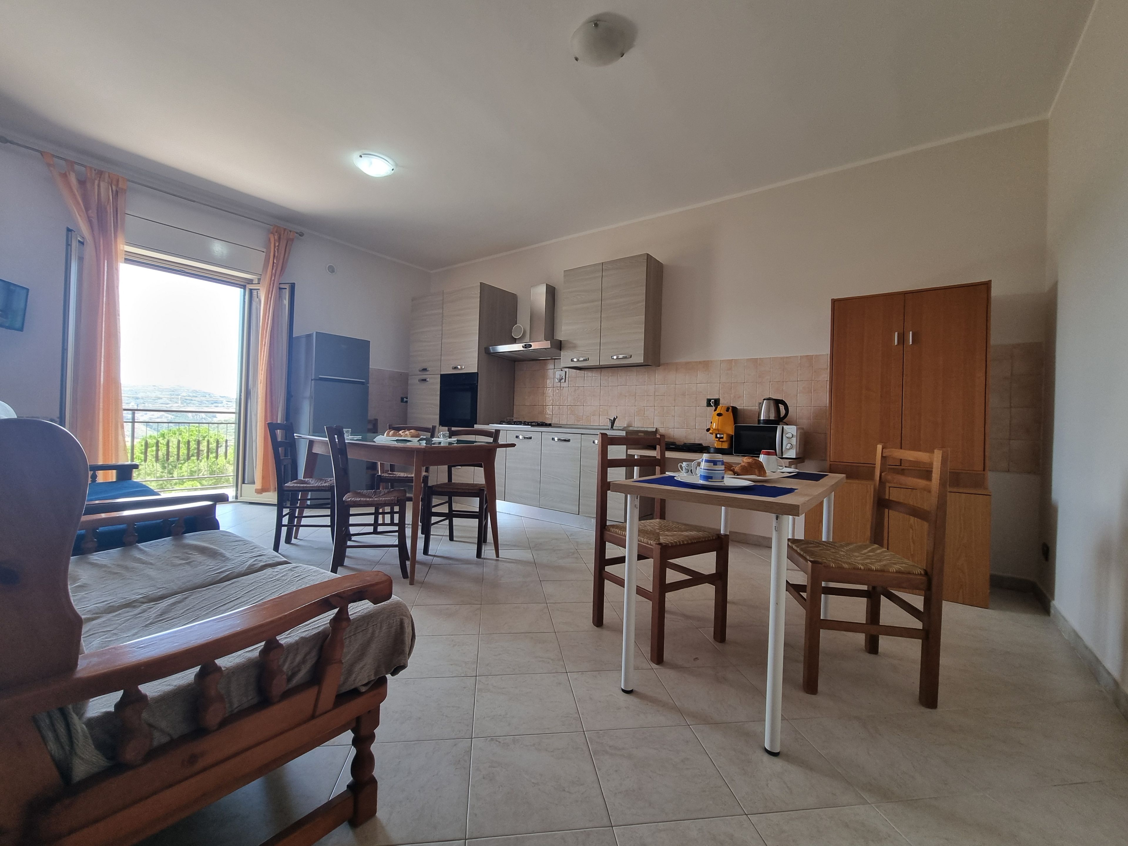 Cozinha moderna com área de refeições, sofá e vista para o exterior.