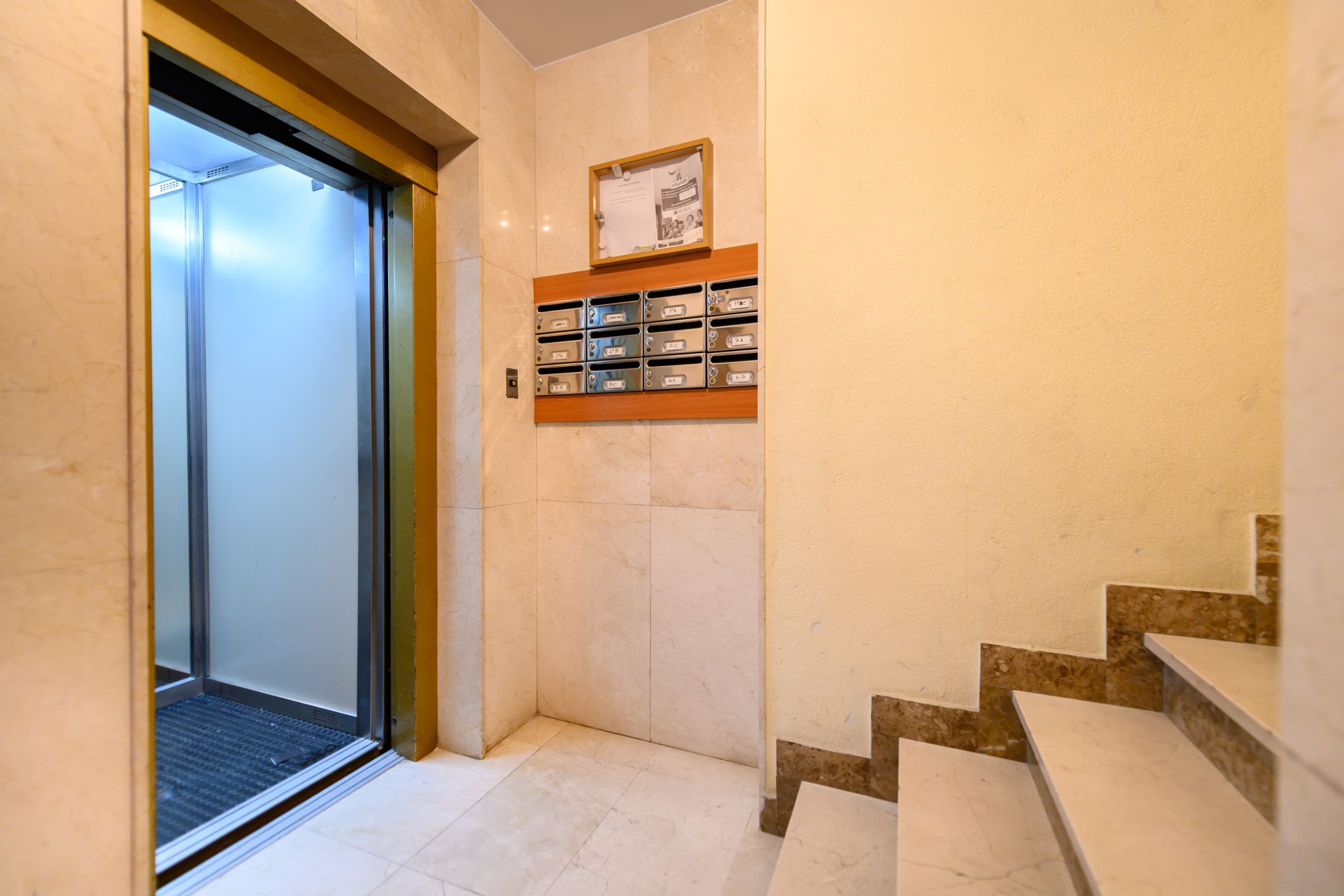 Um hall de hotel com piso de mármore, balcão de recepção e escada.