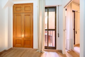 Quarto com guarda-roupa de madeira, porta de vidro deslizante para uma varanda e piso de madeira.