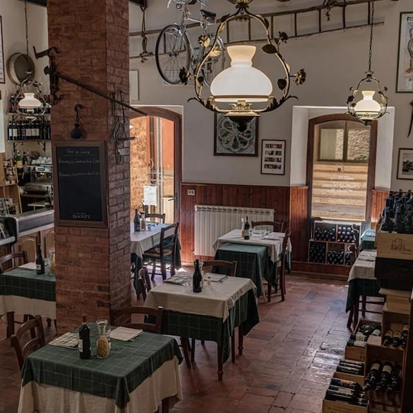 Interior de restaurante com paredes de tijolo, mesas de madeira e luminárias em formato de bicicleta penduradas.