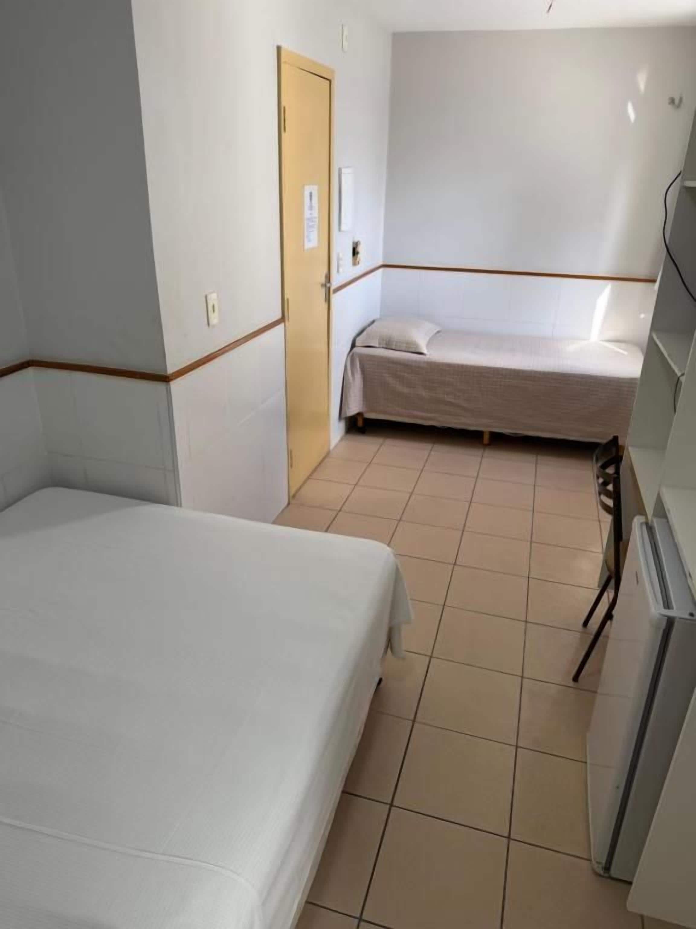 Acomodação compacta com um quarto, cama, escrivaninha e geladeira.