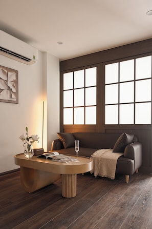 Uma sala de estar moderna com sofá, mesa de centro e uma janela grande.