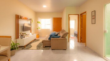 Uma sala de estar moderna com sofá, televisão e plantas em vasos.