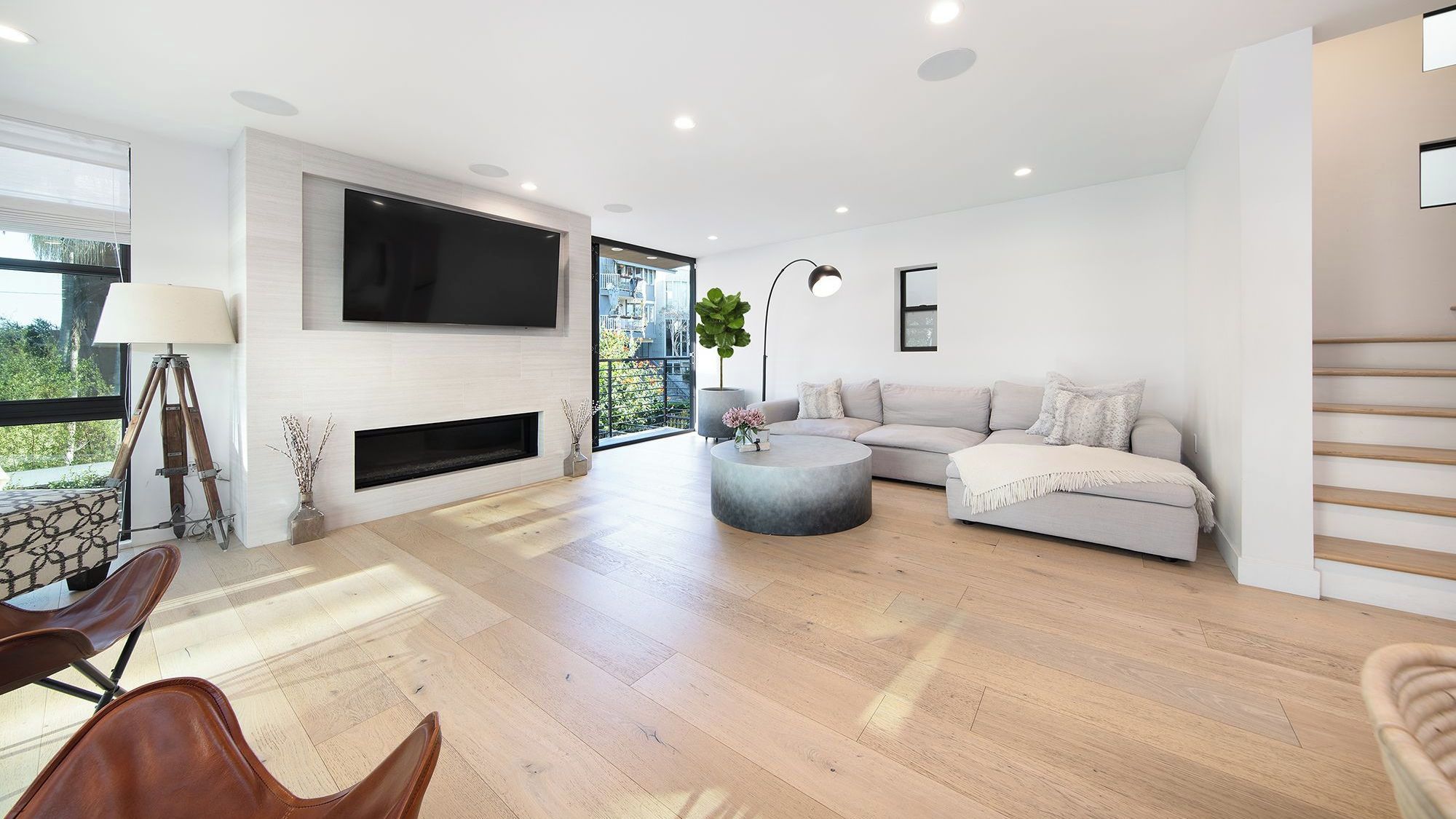 Uma sala de estar moderna com televisão de tela plana, lareira, sofá, mesa de centro e escada.