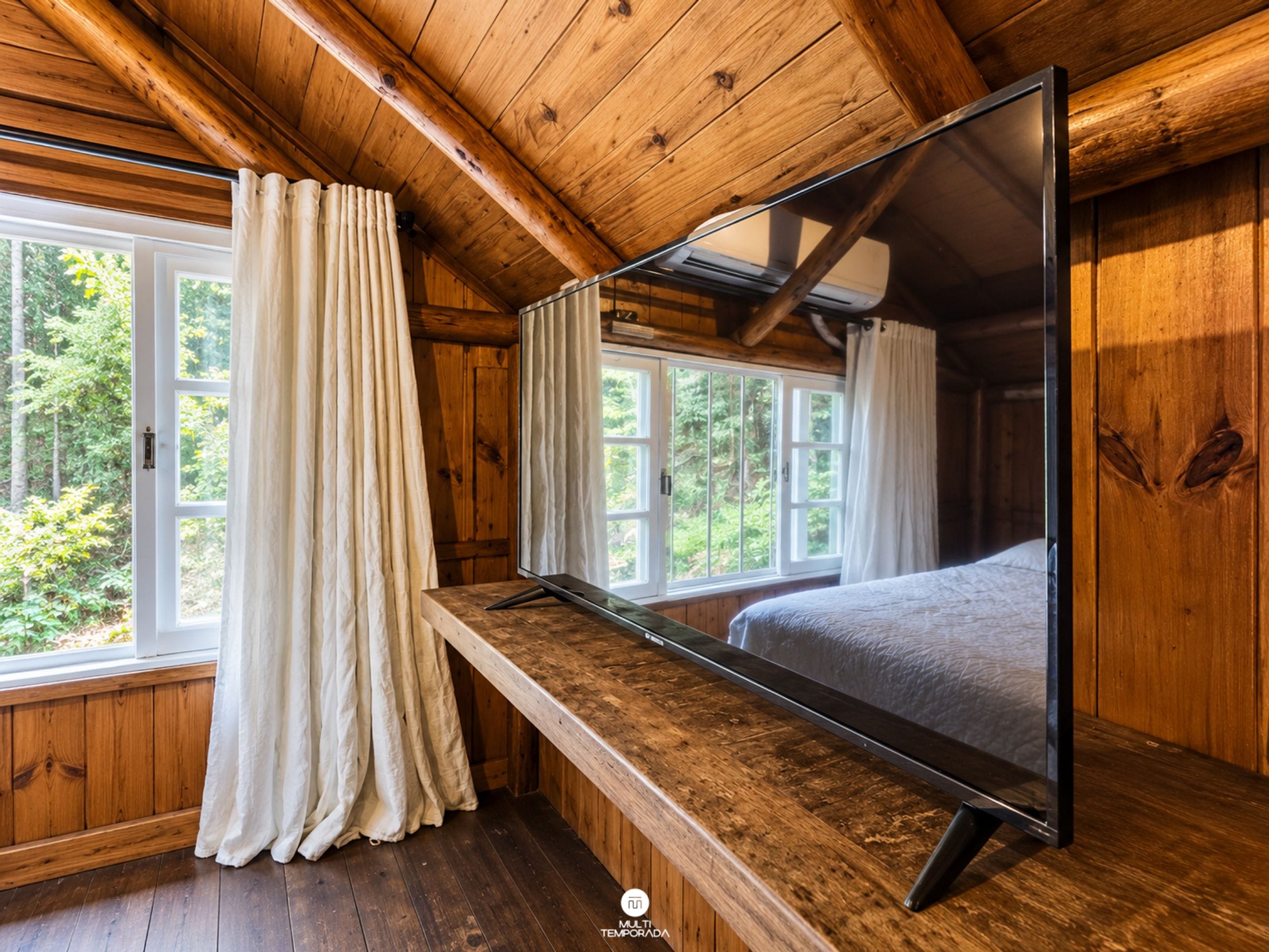 Quarto de cabana de madeira com um espelho grande que reflete uma cama e janelas.