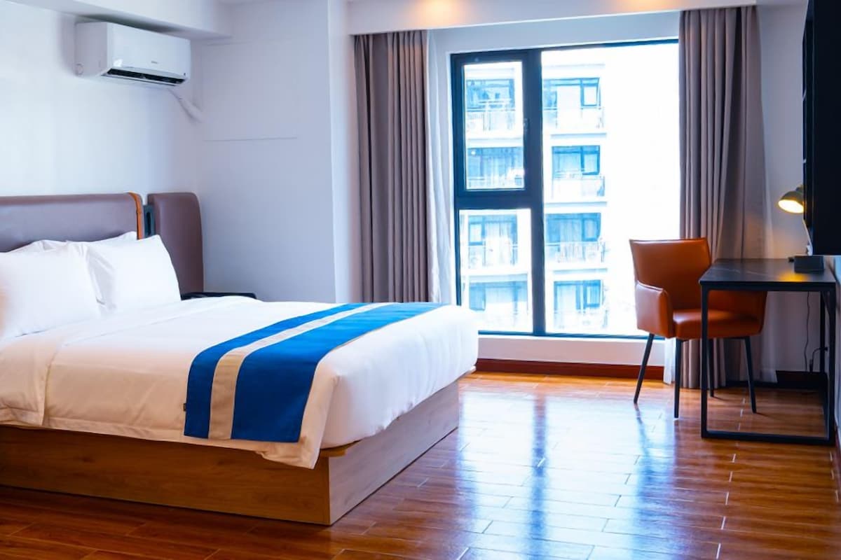 Quarto de hotel com cama, escrivaninha e vista para a cidade.