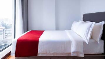 Quarto de hotel com cama, janela com cortinas e vista para prédios.