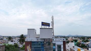Um edifício de hotel com uma placa de identificação, rodeado por outros edifícios e um céu claro.