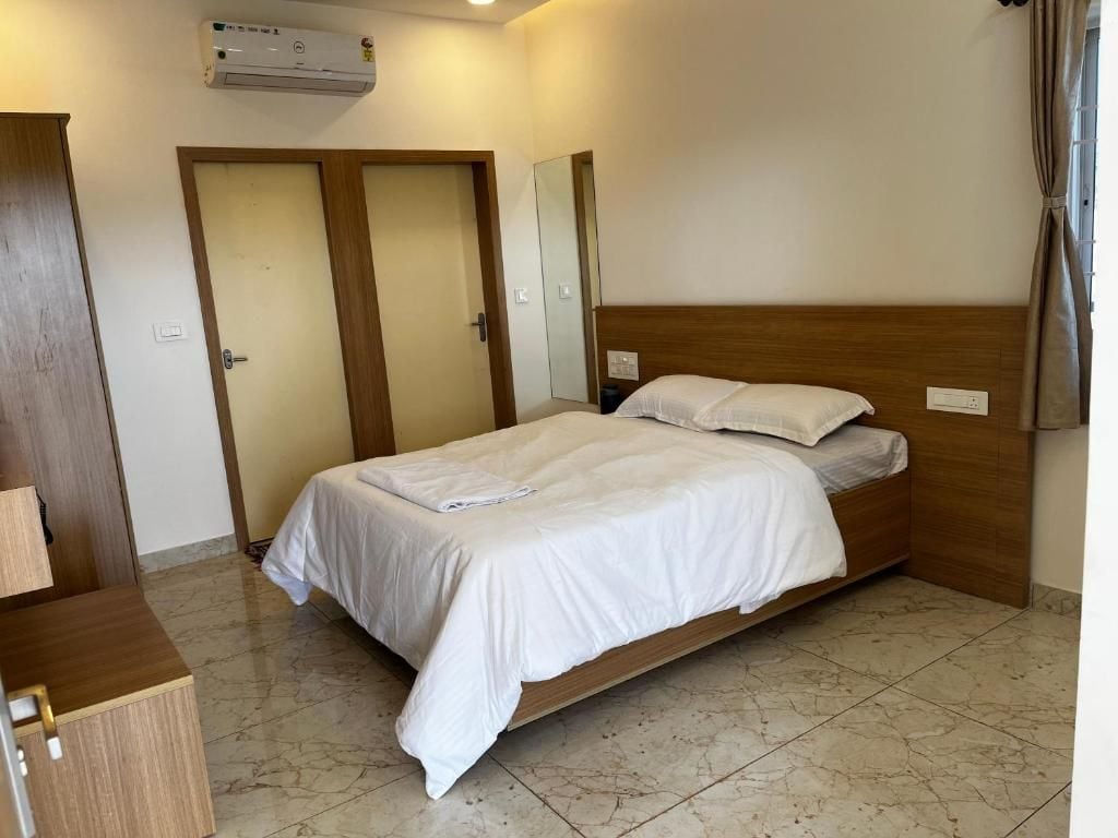 Quarto com cama, guarda-roupa, espelho e ar condicionado.