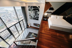 Quarto de hotel moderno com uma cama grande, televisão e vista para a cidade.