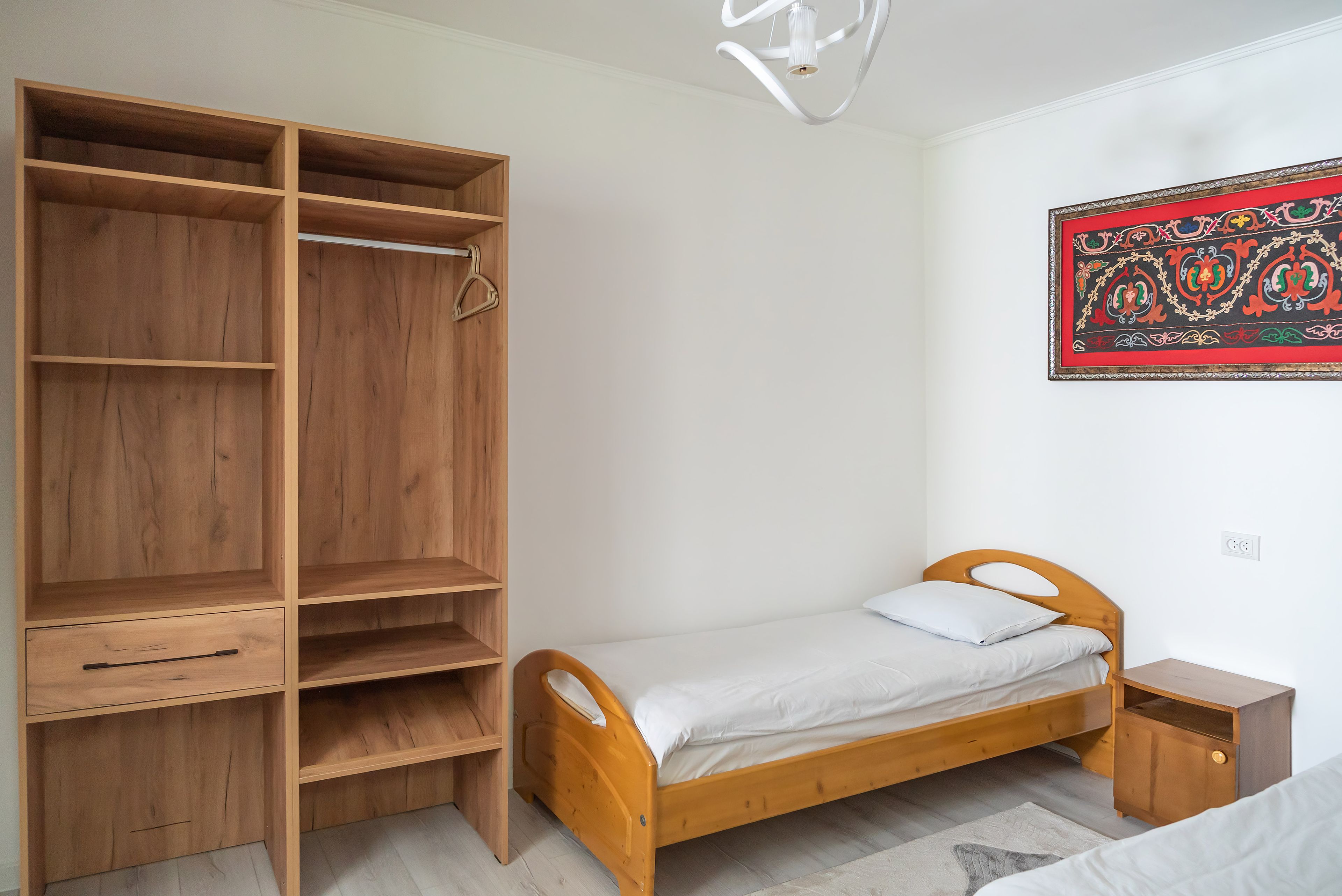 Quarto com cama de madeira, guarda-roupa de madeira e uma pequena mesa de cabeceira.