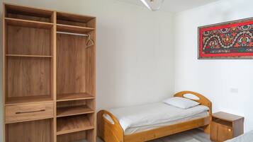 Quarto com cama de madeira, guarda-roupa de madeira e uma pequena mesa de cabeceira.