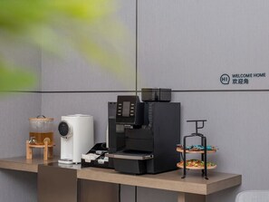 Máquina de café, dispensador de chá e uma mesa com frutas.