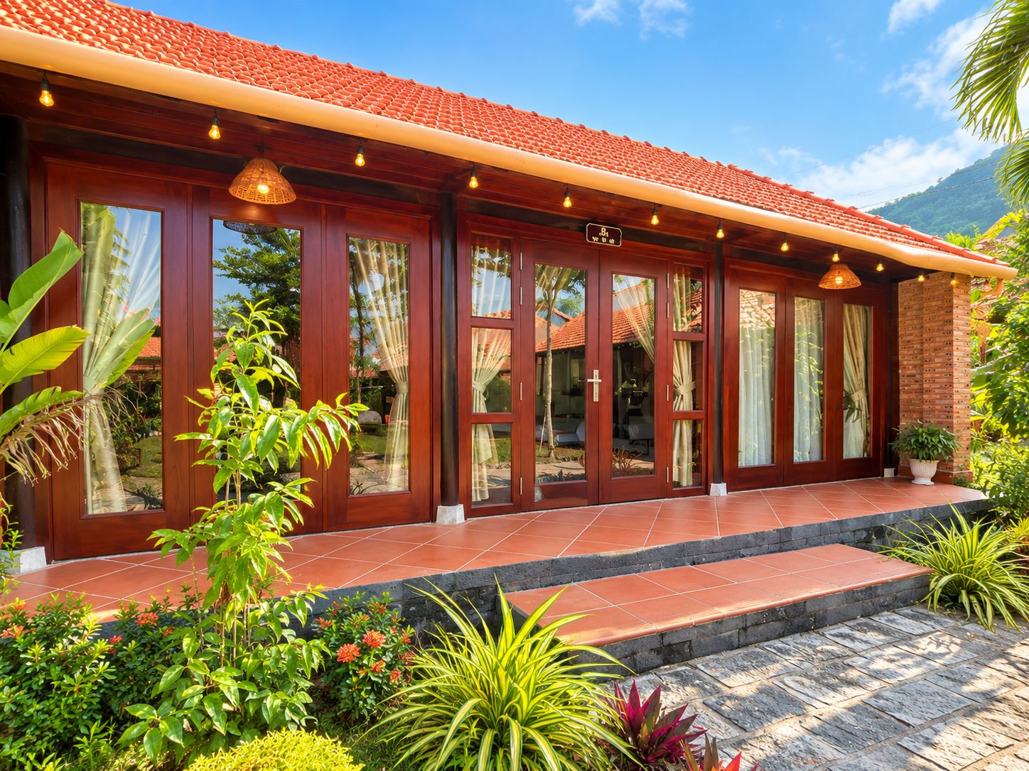 Um hotel com telhado de telhas vermelhas, grandes portas de vidro e um jardim bem cuidado.