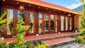 Um hotel com telhado de telhas vermelhas, grandes portas de vidro e um jardim bem cuidado.