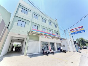 Um edifício de vários andares com uma fachada comercial exibindo uma placa da Indomaret.