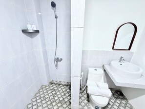 Casa de banho com chuveiro, sanita e lavatório, e um espelho.