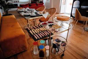 Disposição para o café da manhã com croissants, doces e uma variedade de frutas sobre uma mesa.