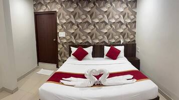Quarto de hotel com uma cama, parede com padrões geométricos, uma porta e arrumação de toalhas sobre a cama.