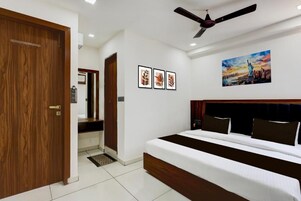 Quarto com cama, ventilador de teto e quadros nas paredes.