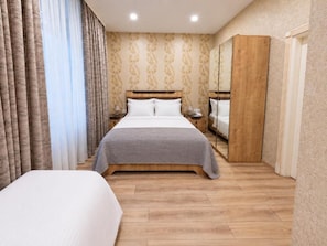 Quarto de hotel com uma cama grande, mesas de cabeceira, um guarda-roupa e um espelho.