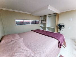 Quarto com cama, janela, guarda-roupa e ventoinha.
