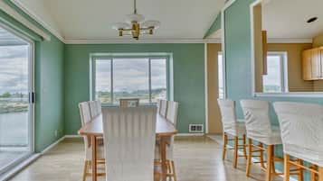 Uma área de refeições com mesa, cadeiras, janelas amplas e vista para o exterior.