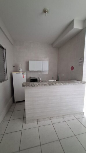 Cozinha com armários brancos, geladeira e bancada.