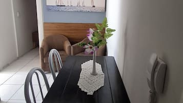 Uma sala de jantar com uma mesa, cadeiras, um vaso de flores e um quadro na parede.