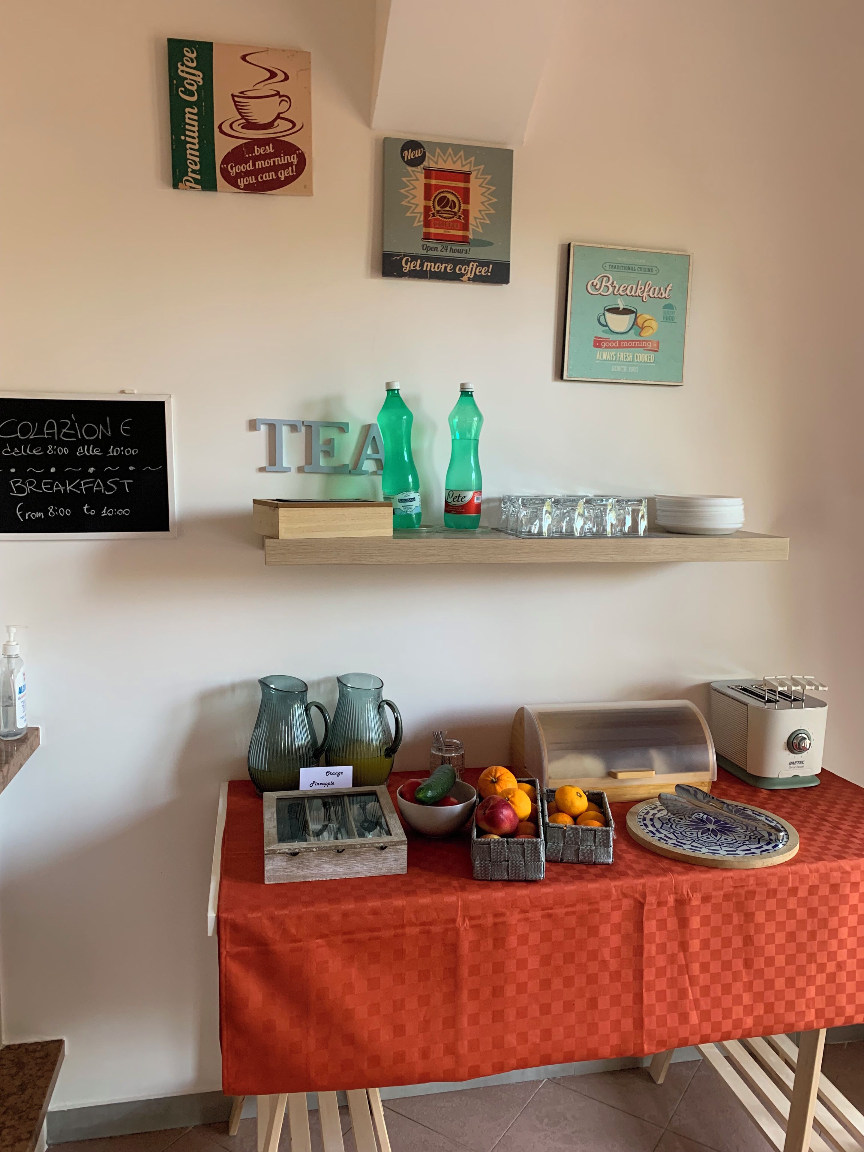 Disposição para o café da manhã com cardápio em lousa, garrafas de chá e uma torradeira em cima da mesa.