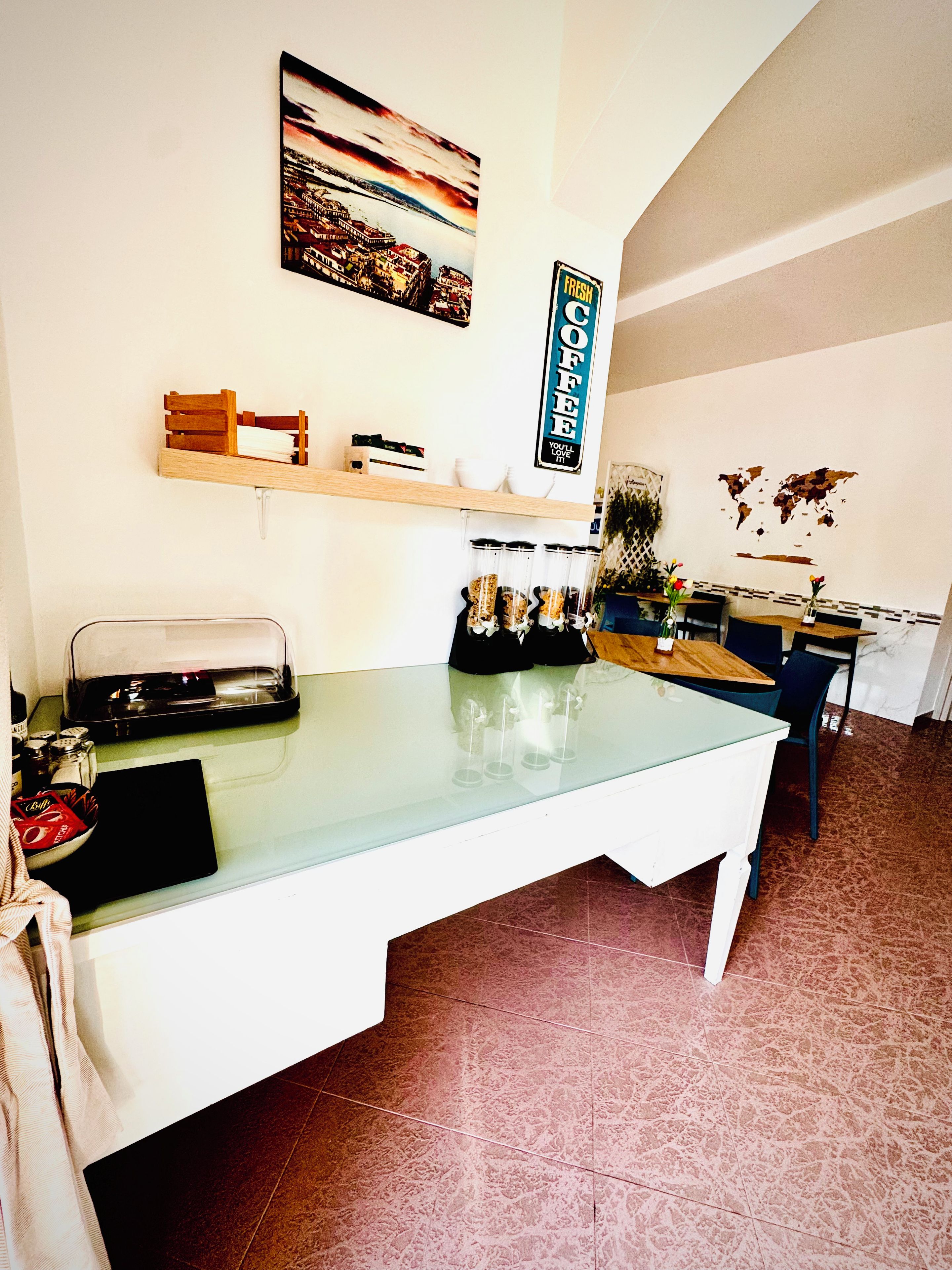 Cozinha moderna com mesa de vidro, prateleiras de madeira e um mapa-múndi na parede.