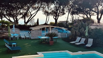 Um quintal com piscina, espreguiçadeiras e área de varanda.