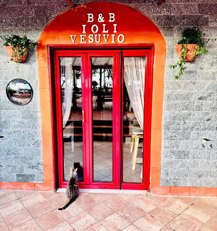 Entrada de um edifício com arco vermelho e a inscrição 'B&B IOLI VESUVIO' em destaque.