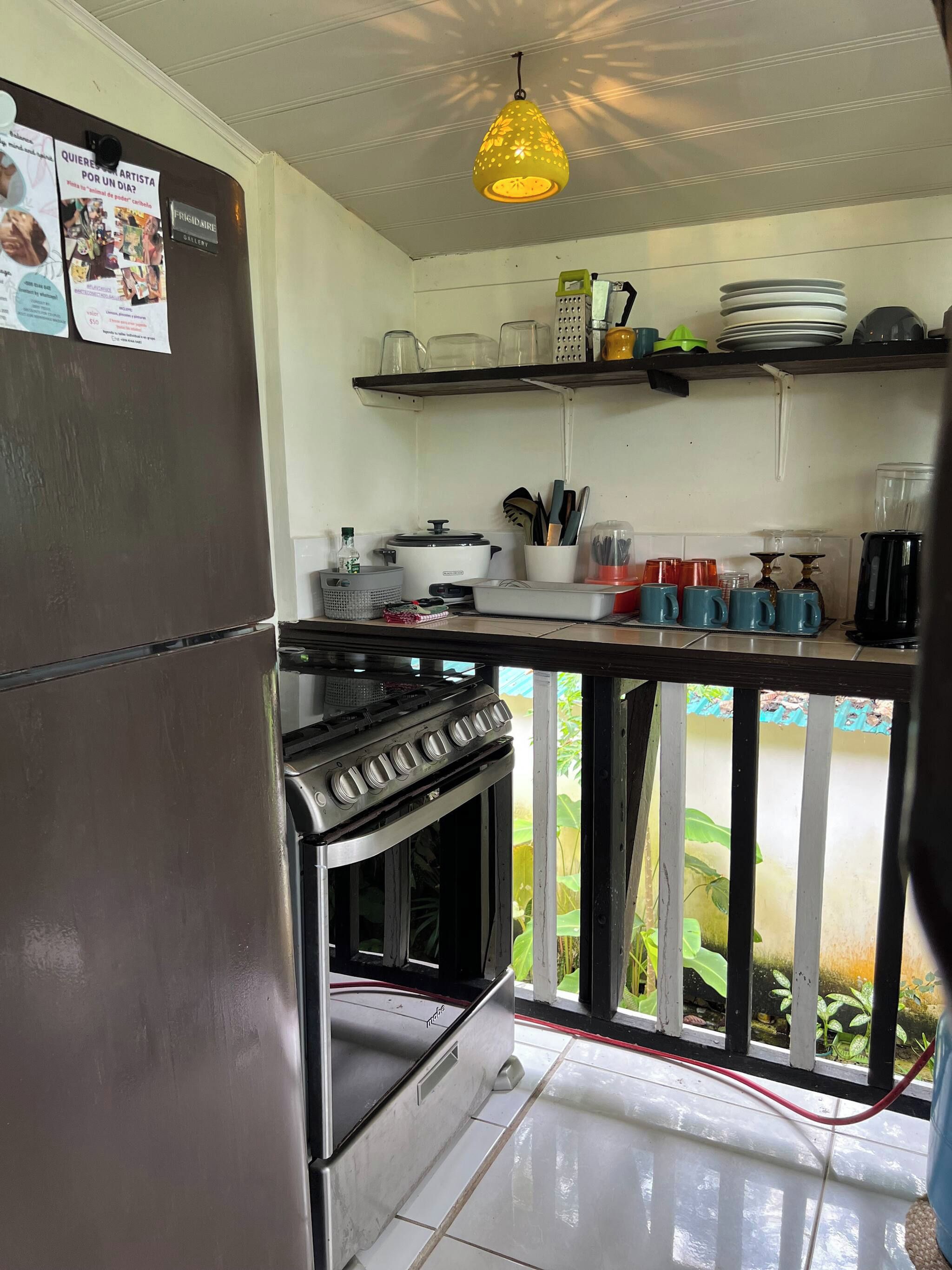 Cozinha equipada com geladeira, fogão e luminária suspensa.