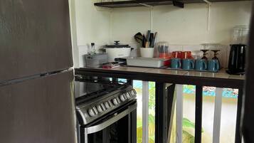 Cozinha equipada com geladeira, fogão e luminária suspensa.