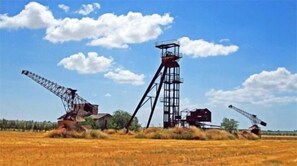 Uma grande estrutura industrial com uma torre alta e duas guindastes em um campo.