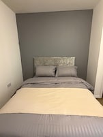 Uma cama com cabeceira, duas almofadas e um cobertor.