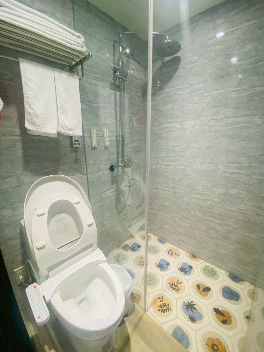 Casa de banho com sanita, cabine de duche e porta-toalhas.