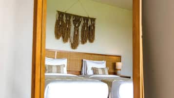 Quarto com duas camas, tapeçaria pendurada, ventilador de teto e cabeceira de madeira.