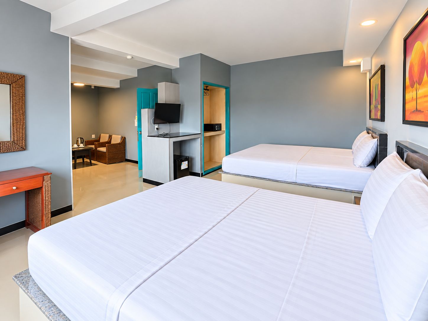 Quarto de hotel com duas camas, uma escrivaninha, televisão e banheiro.