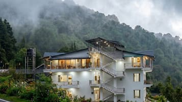 Um hotel com vários andares, varandas, uma escadaria e um jardim.